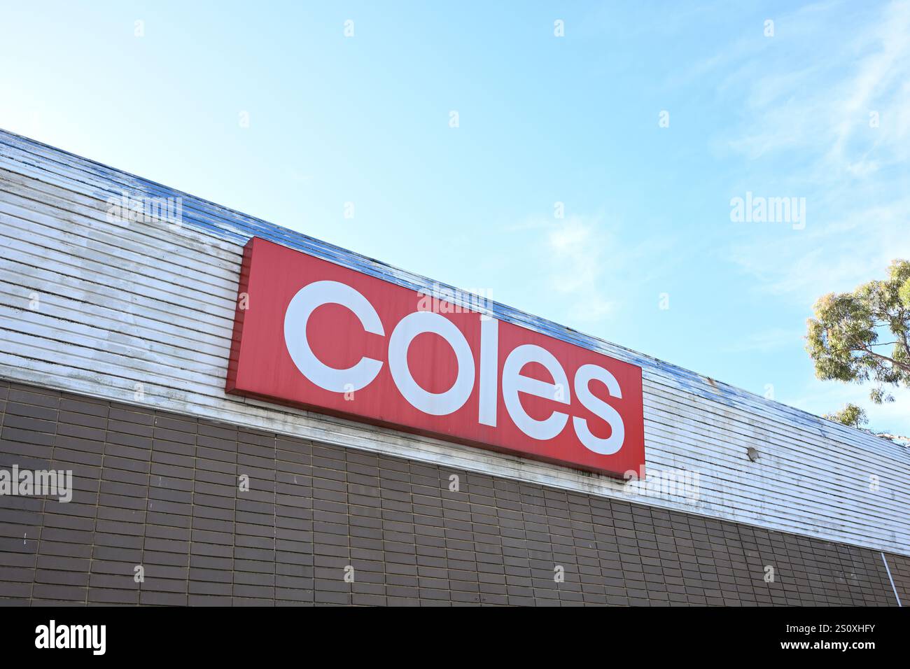 Red and white Coles supermarket logo on the side of an old brown brick ...