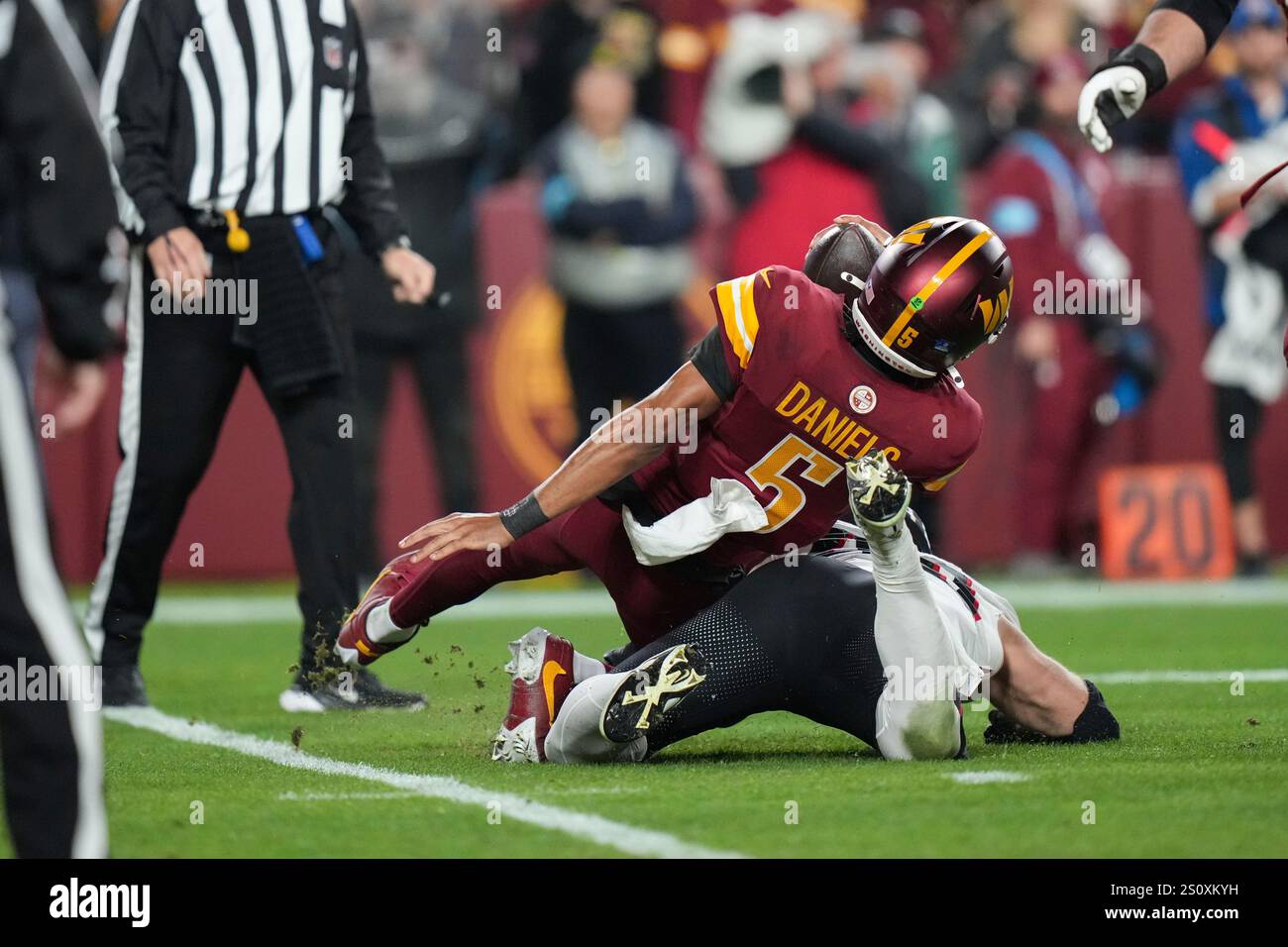 Washington Commanders quarterback Jayden Daniels (5) is brought down by ...