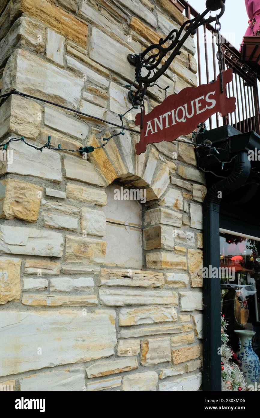 Antiques sign hanging from a wrought iron hanger on a stone finished ...