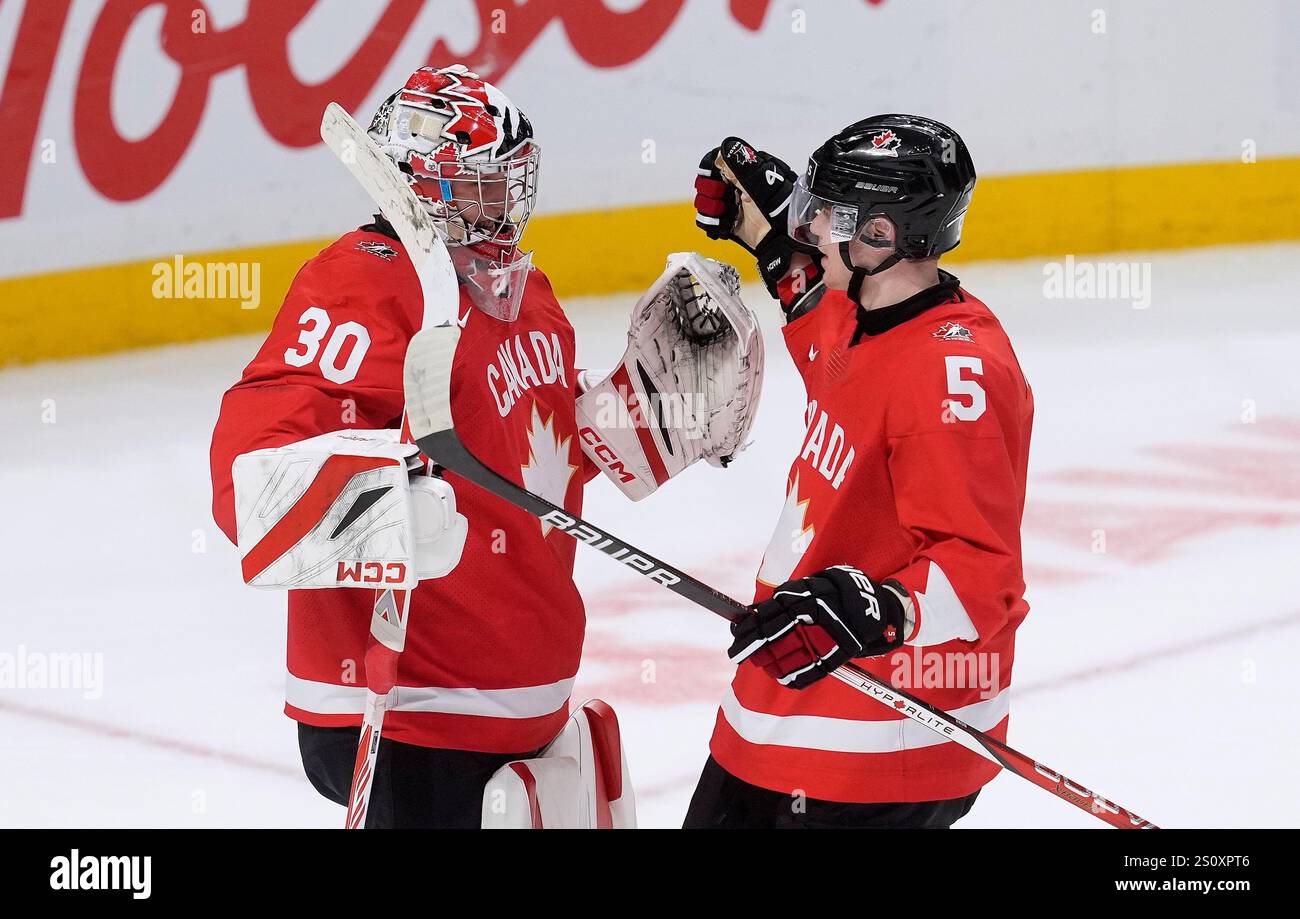 Canada goaltender Carter George and teammate Oliver Bonk (5) celebrates ...