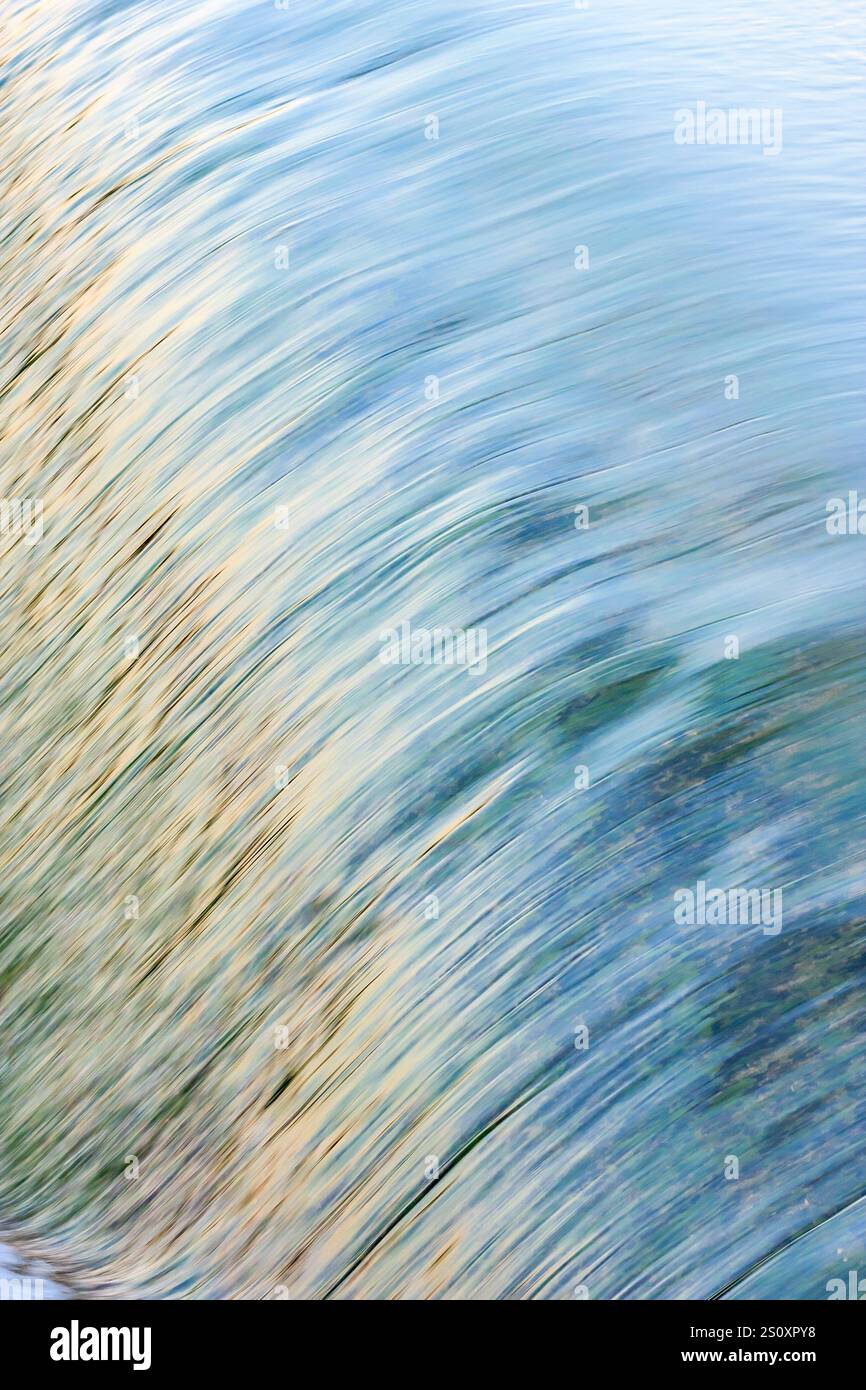 The image is a blurry reflection of a waterfall in the water. The water ...