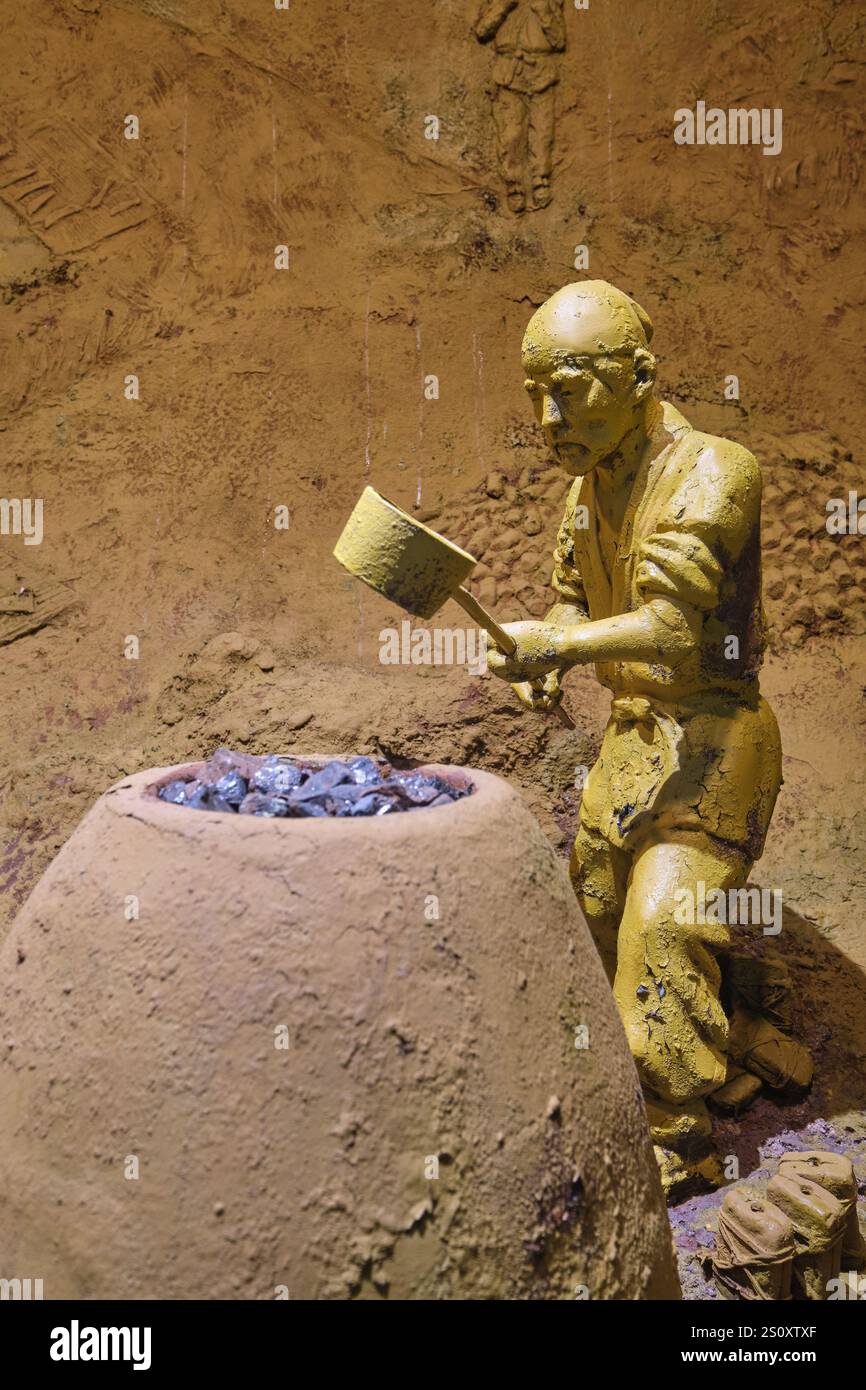 A worker busy smelting, making iron in a basic, village fire pit area ...