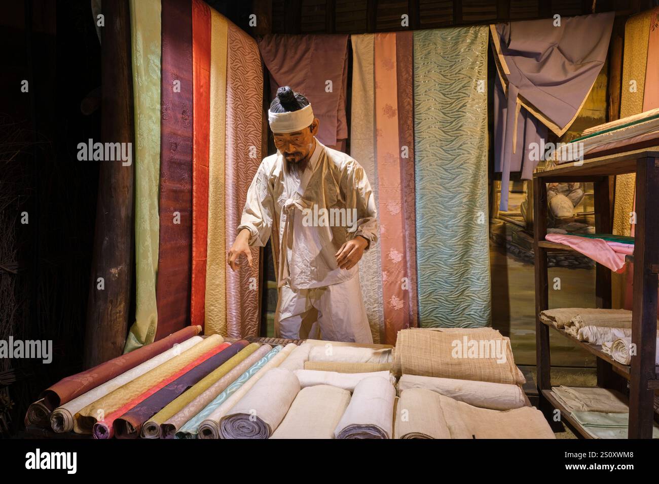 A man vendor, merchant selling fabric, textiles in bolts, rolls at his ...