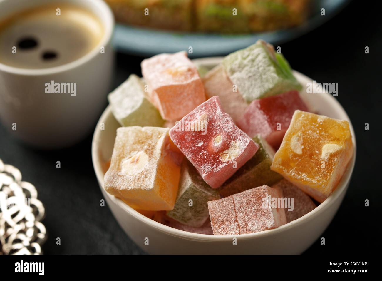 Colorful Turkish delight served with a cup of coffee on a dark table ...