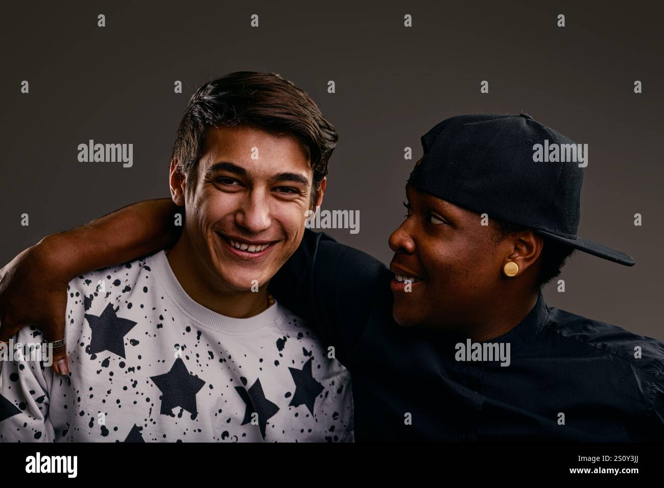 Two young men of different ethnicities smiling and embracing each other ...