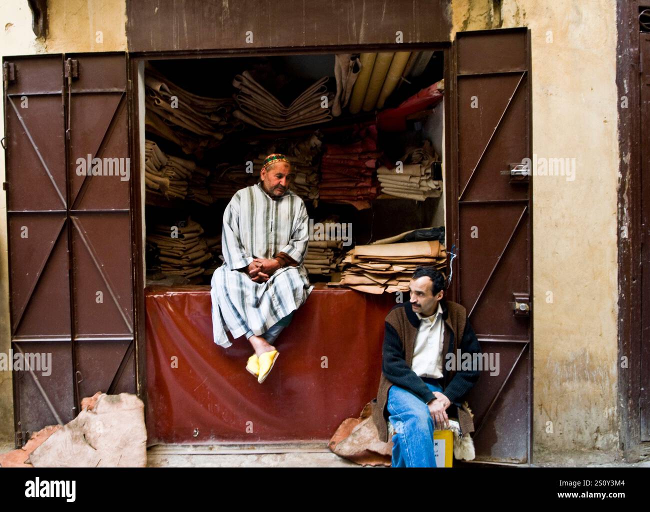 A Moroccan men sitting in the front of his shop in the medina of Fes ...