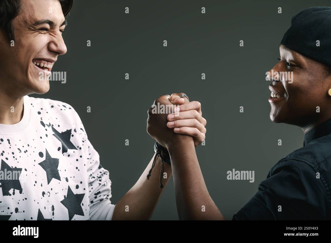 Two happy multi-ethnic young men engaging in a lively arm wrestling ...