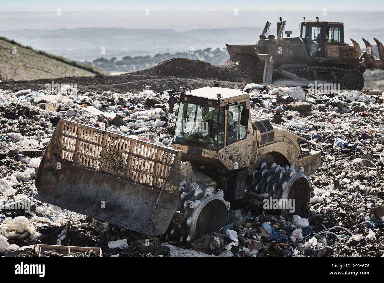 Heavy machinery shredding garbage in an open air landfill. Waste Stock ...