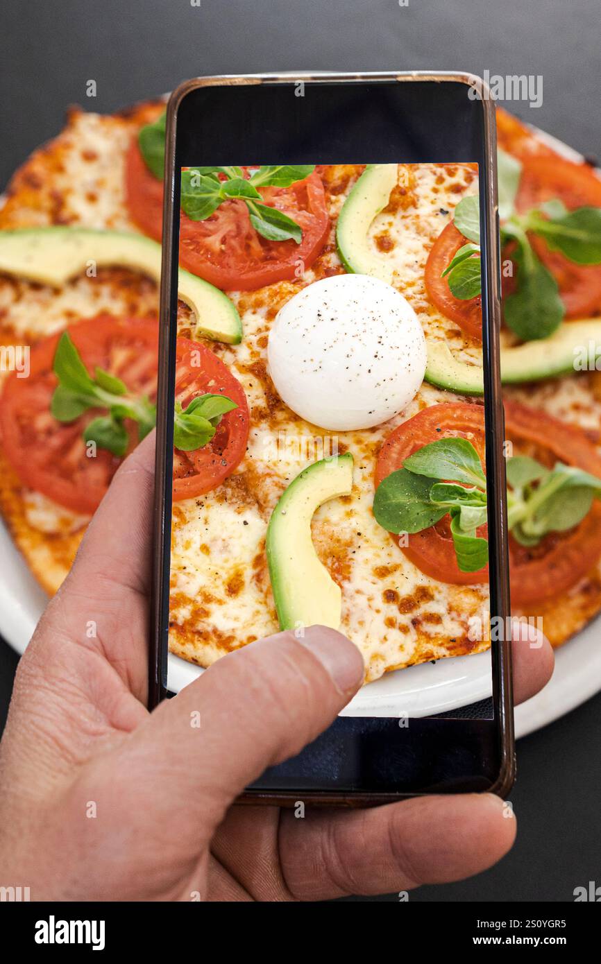Male hand making a photo of pizza with a mobile phone Stock Photo - Alamy