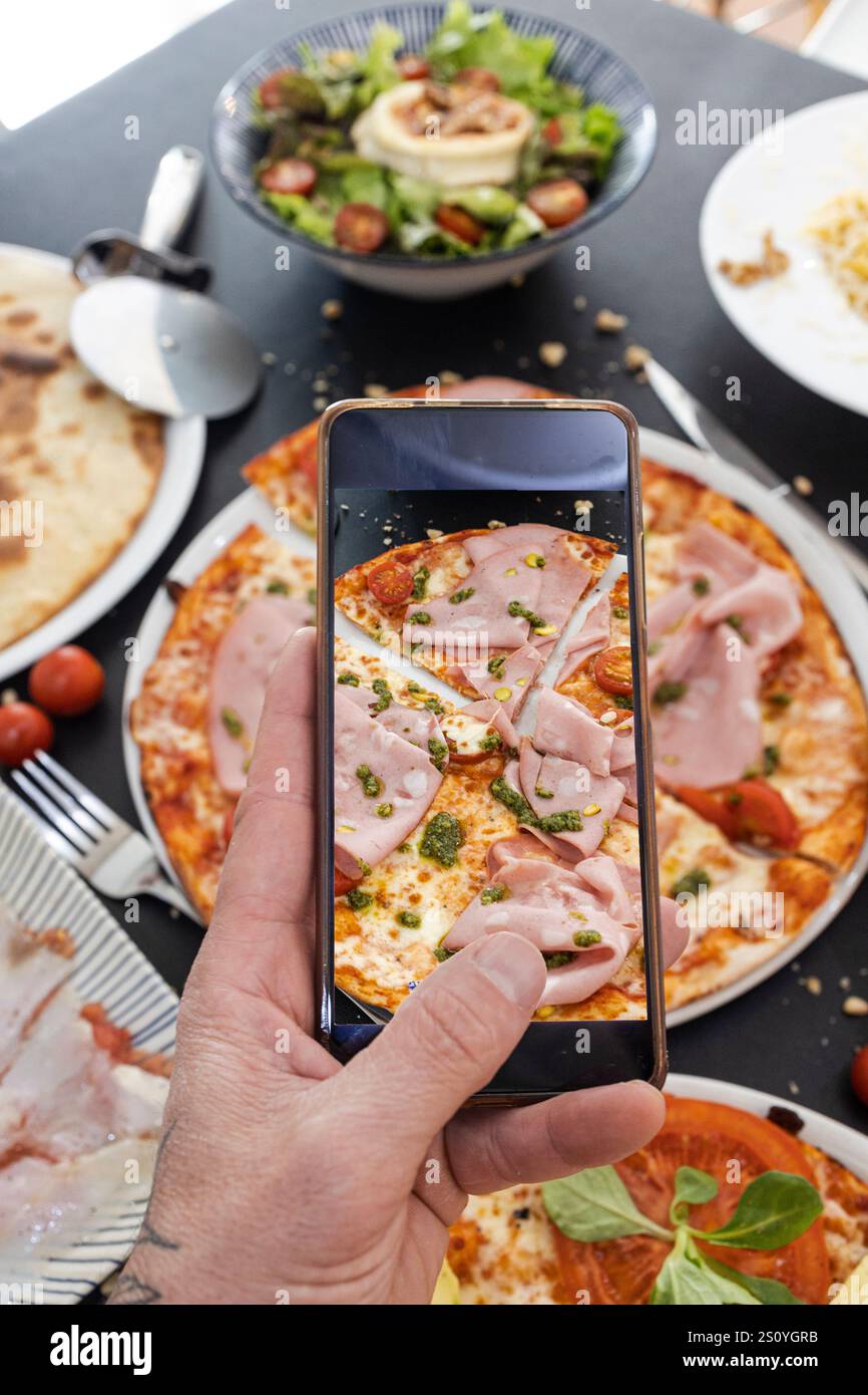 Male hand making a photo of pizza with a mobile phone Stock Photo - Alamy