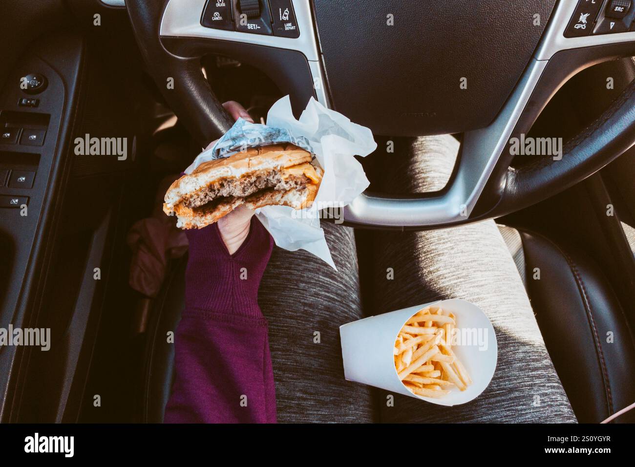 Busy woman eating fast food in car while commuting Stock Photo - Alamy