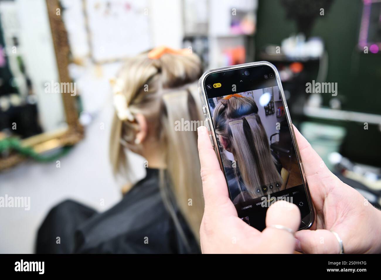 Hair extension application process being photographed on a smart Stock ...