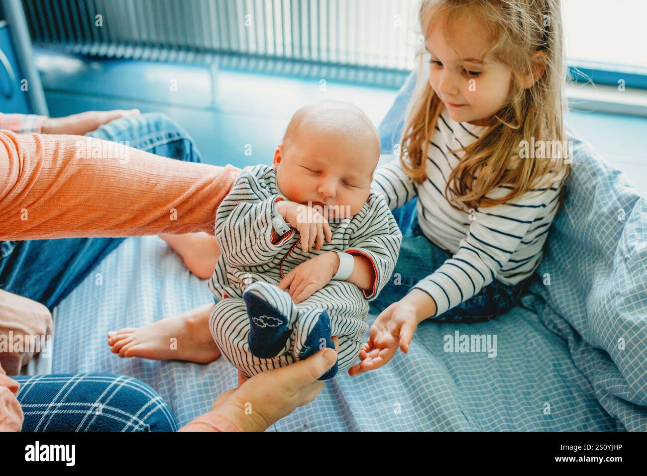 Mom handing newborn baby to older sister at hospital after birth Stock ...