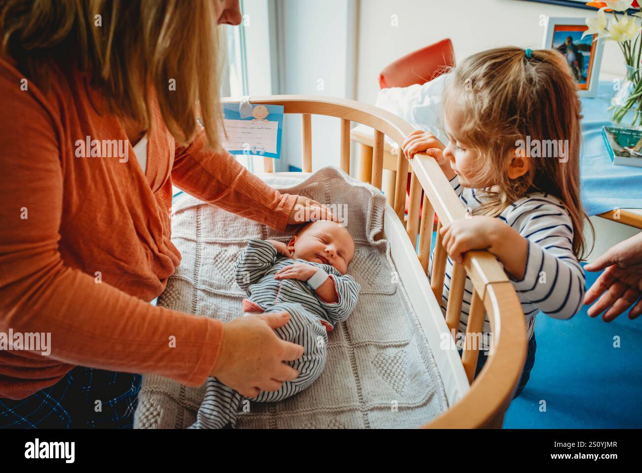 Newborn baby sleeping in hospital bassinet crib with family around ...