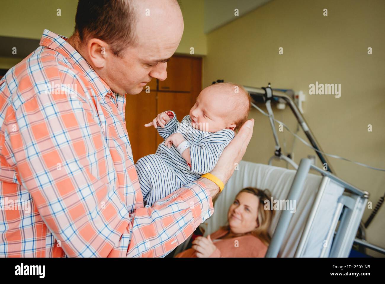 Mom watching dad holding newborn baby at hospital after birth Stock ...