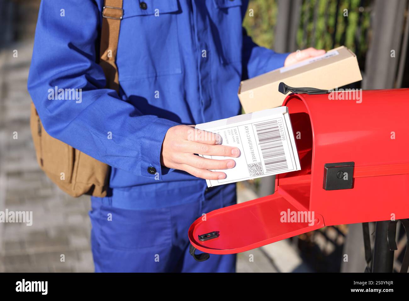Postman putting parcel into mail box outdoors, closeup Stock Photo - Alamy