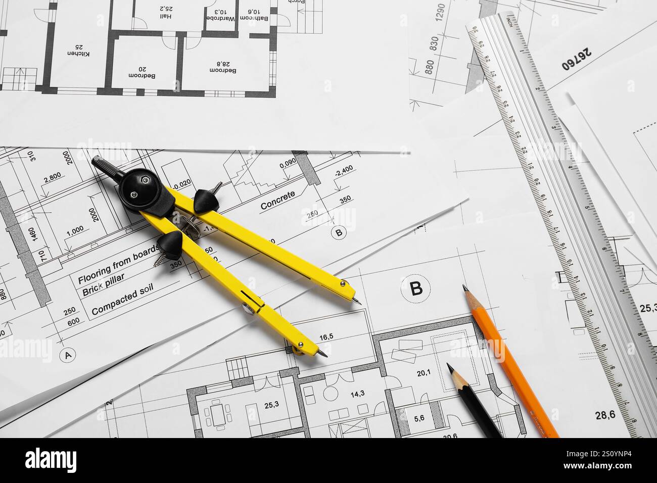 Different architectural drawings, ruler, pencils and divider on table ...