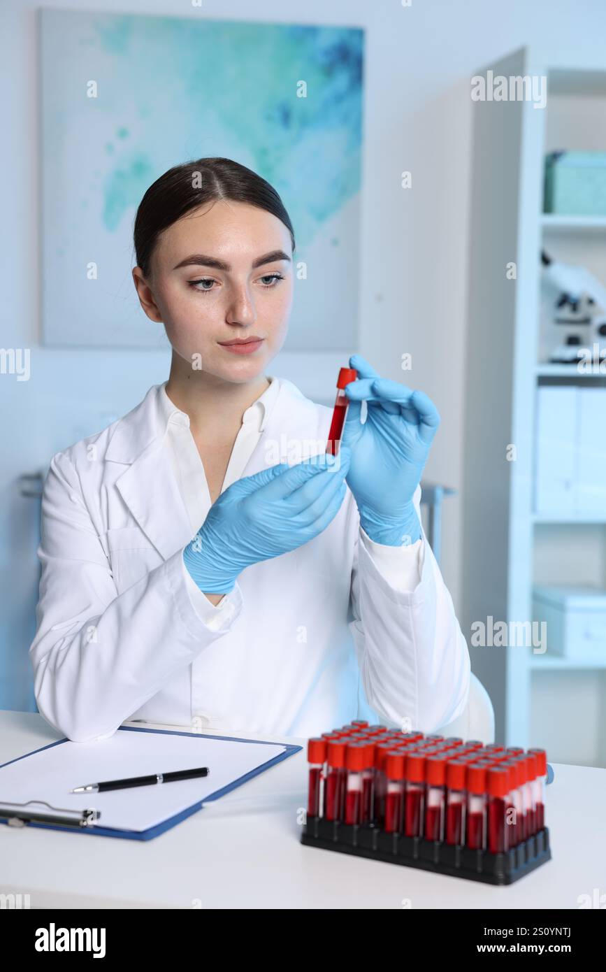 Laboratory testing. Doctor holding test tube with blood sample at table ...