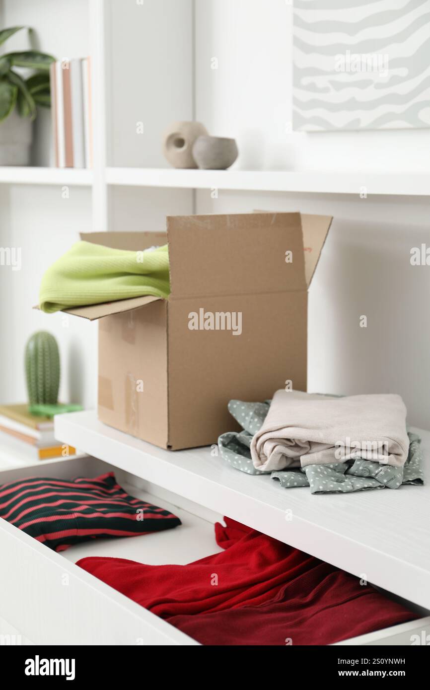 Used clothes and box on chest of drawers indoors Stock Photo - Alamy