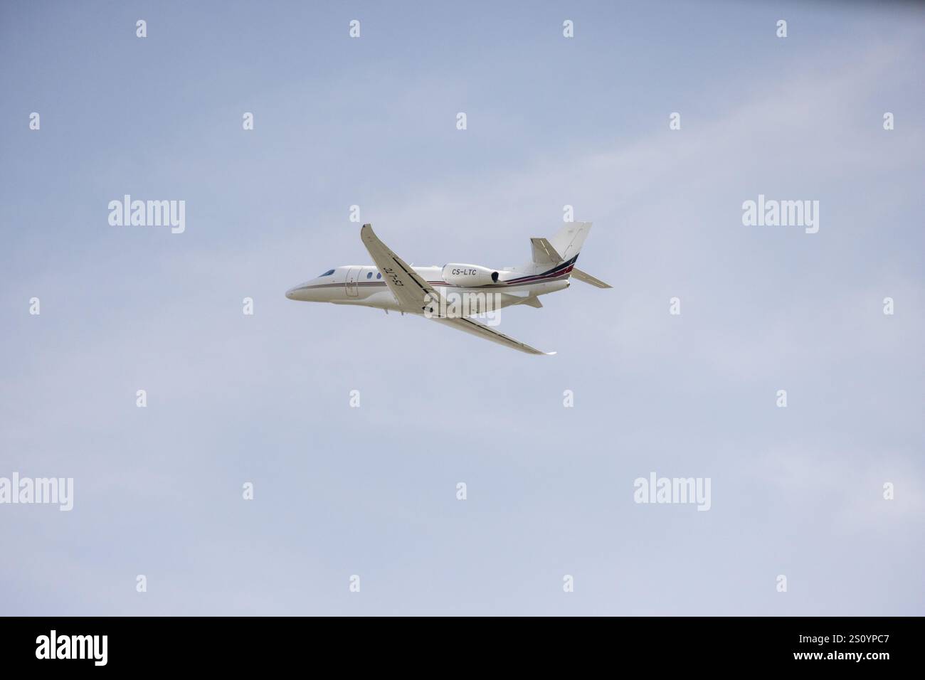White private jet flying over blue sky after taking off from lisbon ...