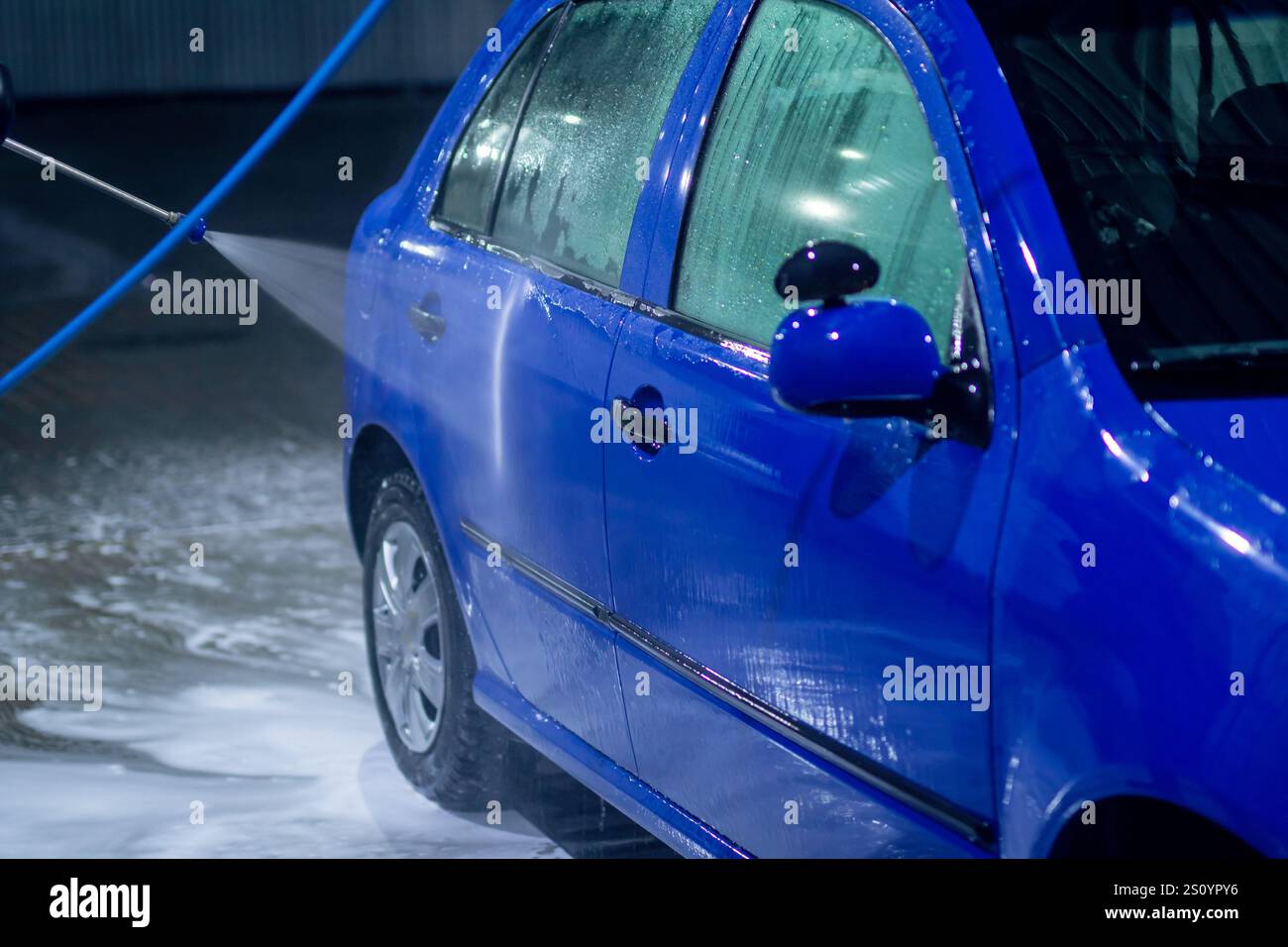 This is a detailed closeup view of the shiny side mirror of a blue car ...