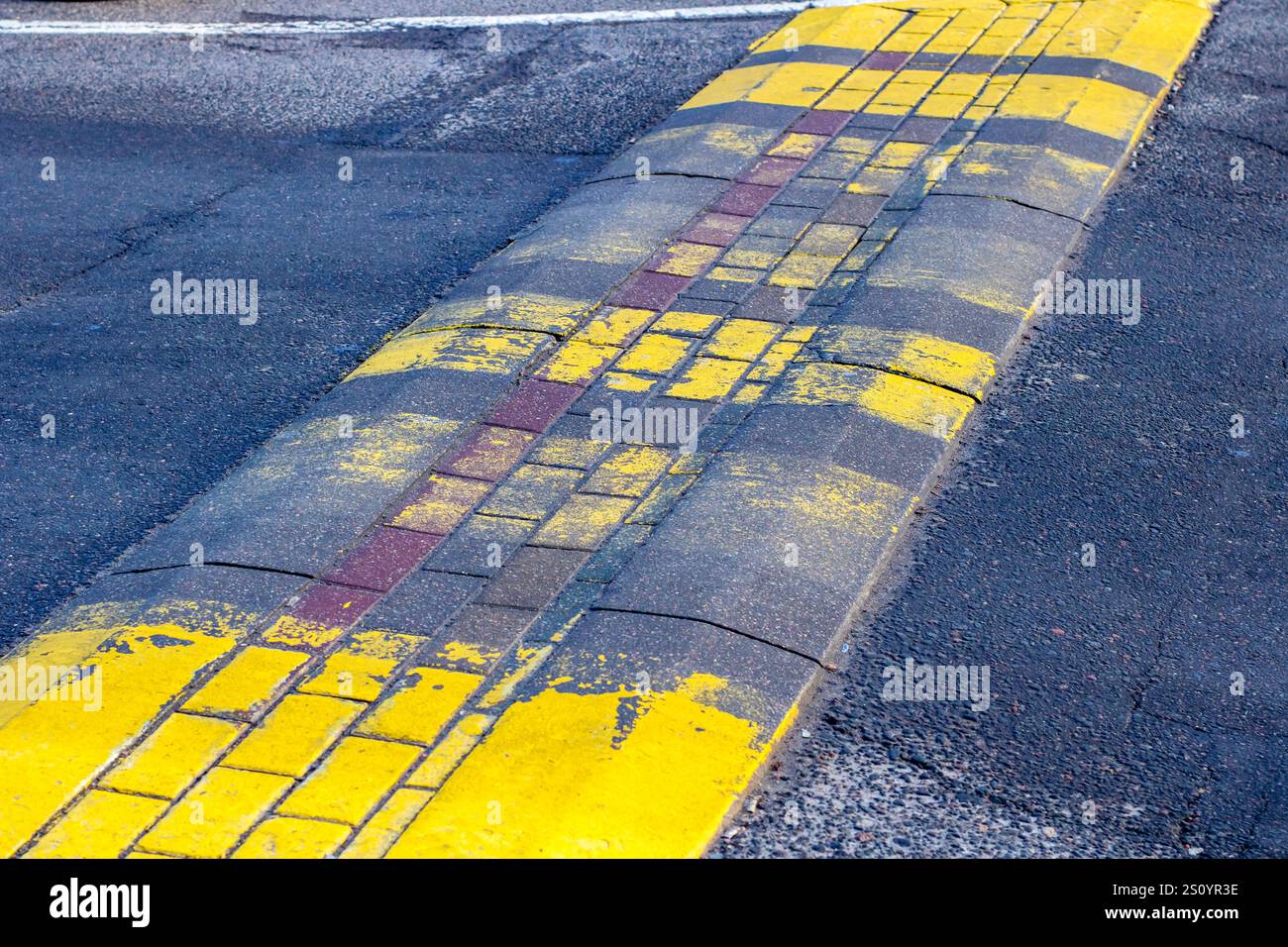 A detailed closeup view of a worn yellow crosswalk marking on dark ...
