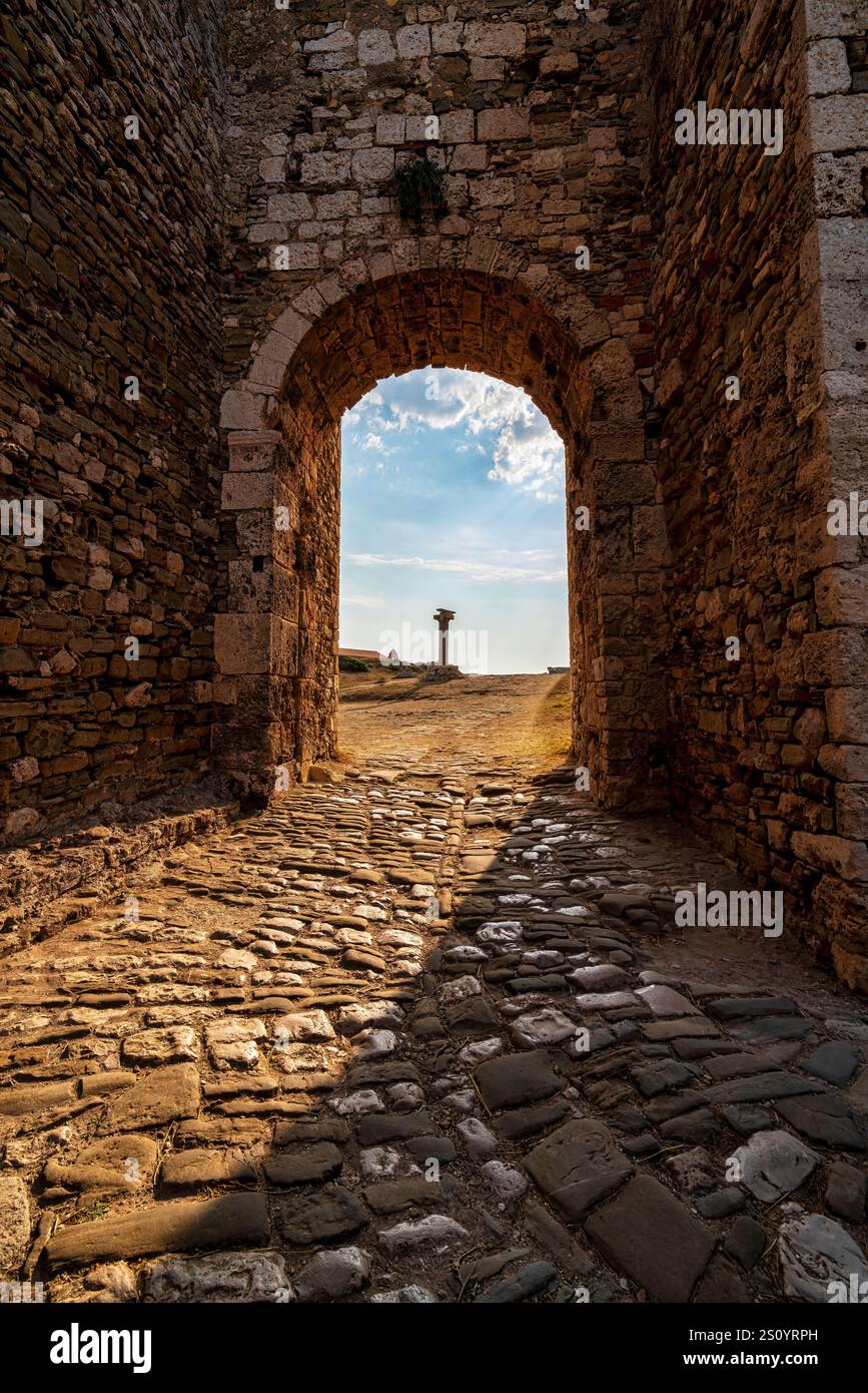Historic stone archway at Methoni Fortress, framing a distant column ...