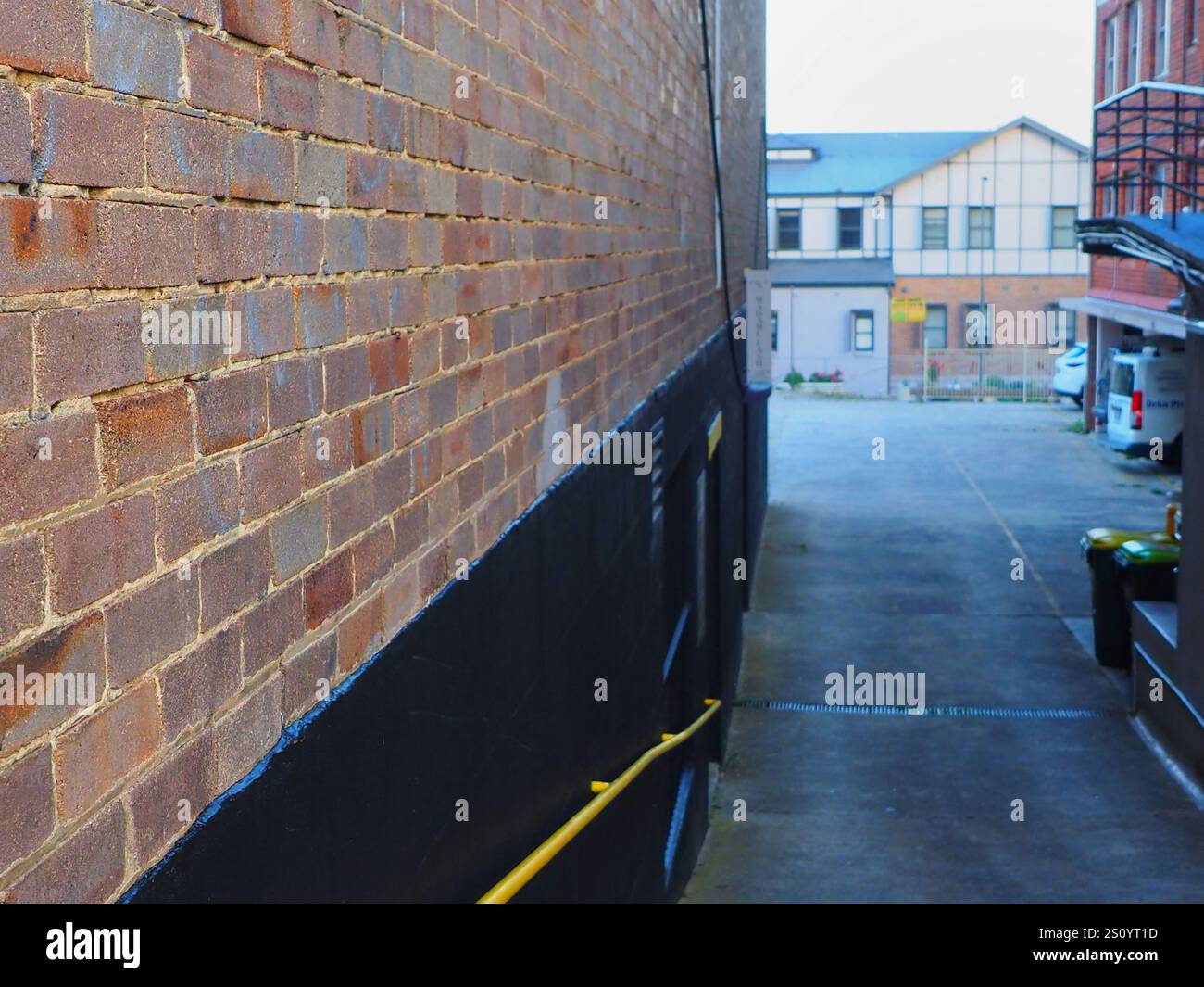 A narrow brick alley with a yellow handrail descends to a quiet ...