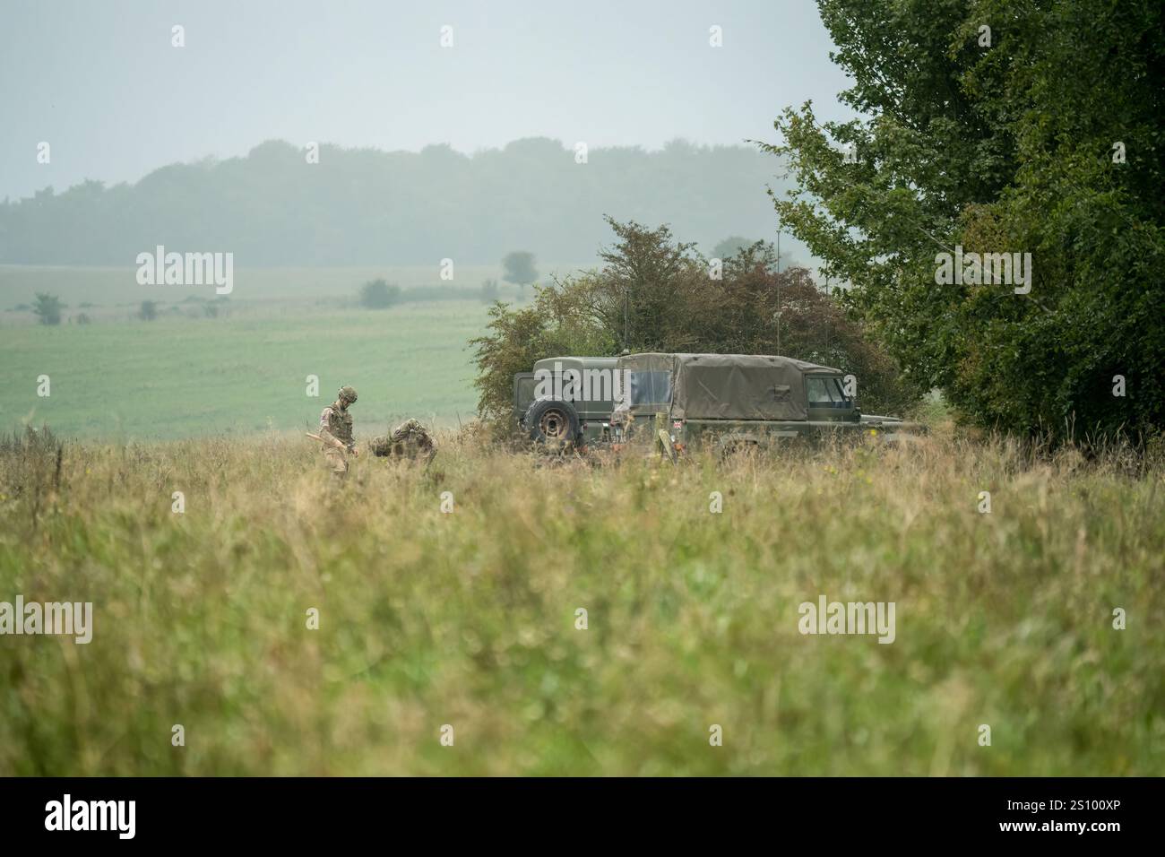British army soldier prepares a field radio aerial mast, near two Land ...