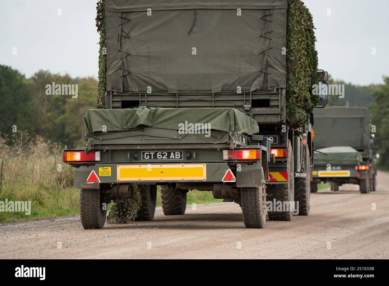 convoy of British army Heavy Utility Trucks driving along a dirt track ...