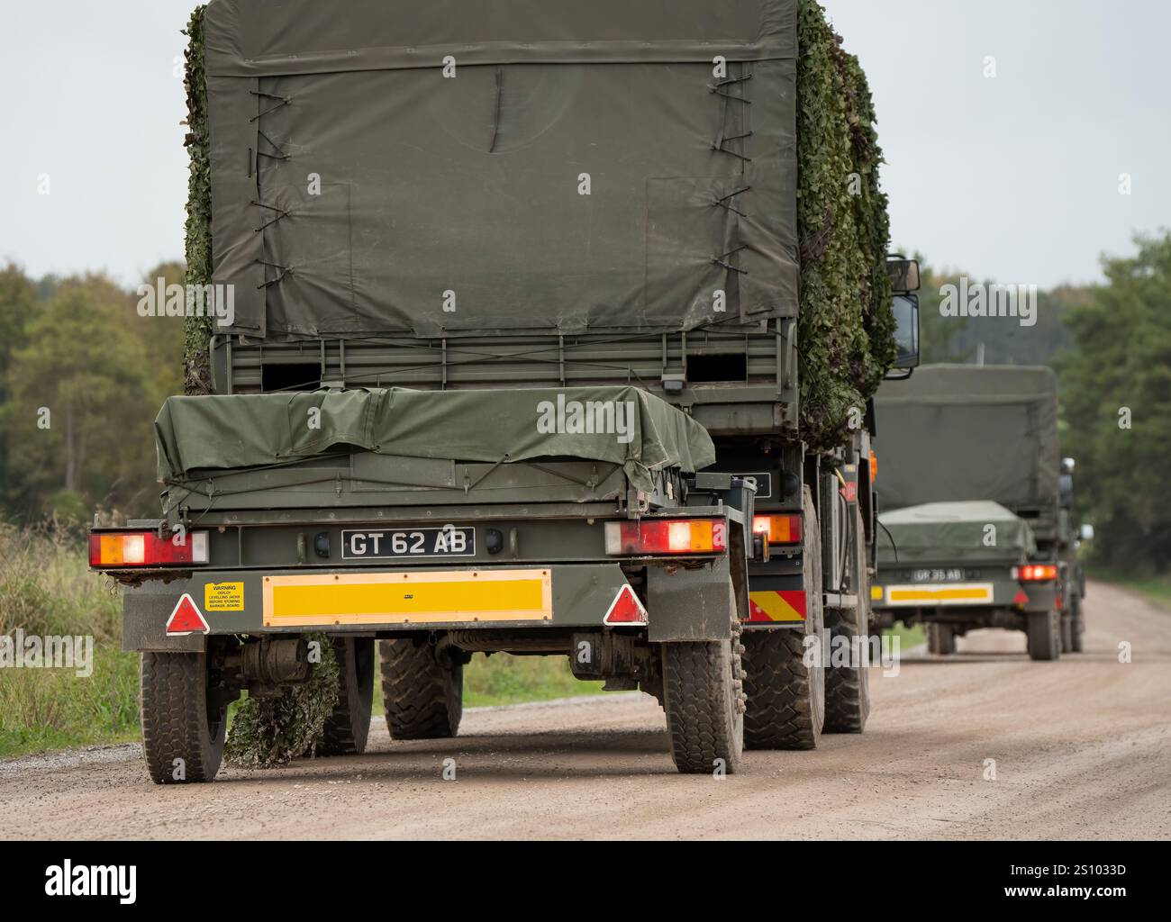 convoy of British army Heavy Utility Trucks driving along a dirt track ...