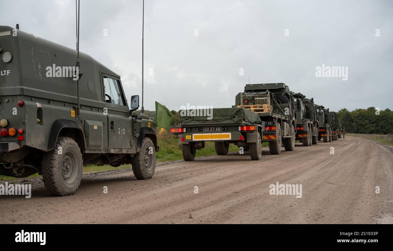 convoy of British army Heavy Utility Trucks driving along a dirt track ...