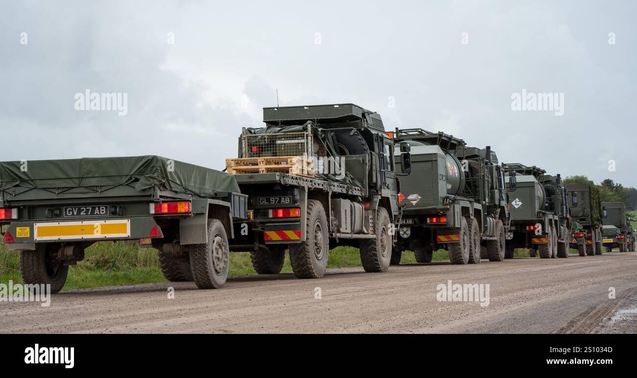 convoy of British army Heavy Utility Trucks driving along a dirt track ...