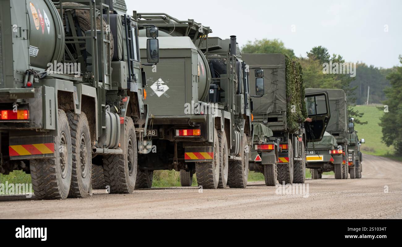 convoy of British army Heavy Utility Trucks driving along a dirt track ...