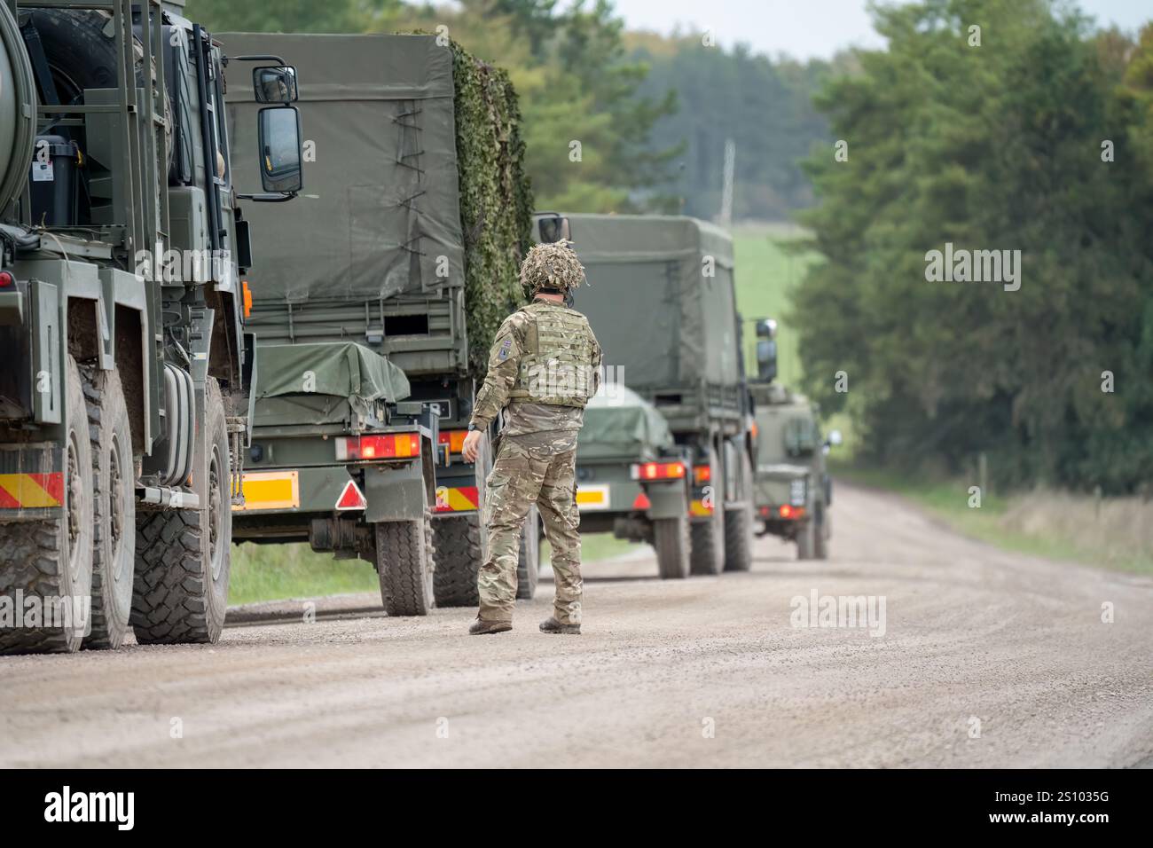 convoy of British army Heavy Utility Trucks driving along a dirt track ...