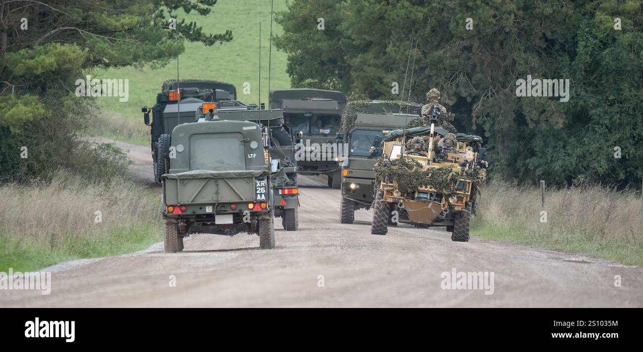 convoy of British army Heavy Utility Trucks driving along a dirt track ...