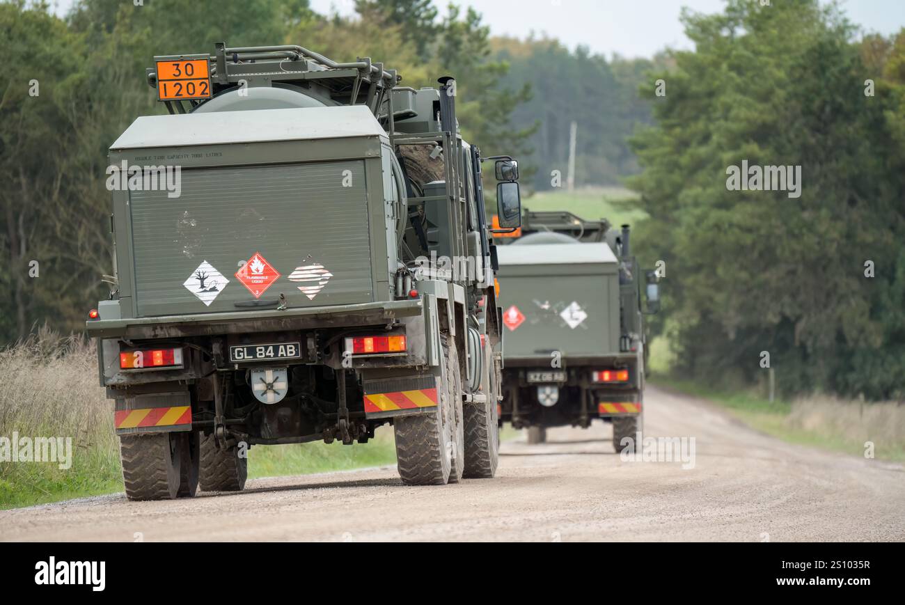 convoy of British army Heavy Utility Trucks driving along a dirt track ...