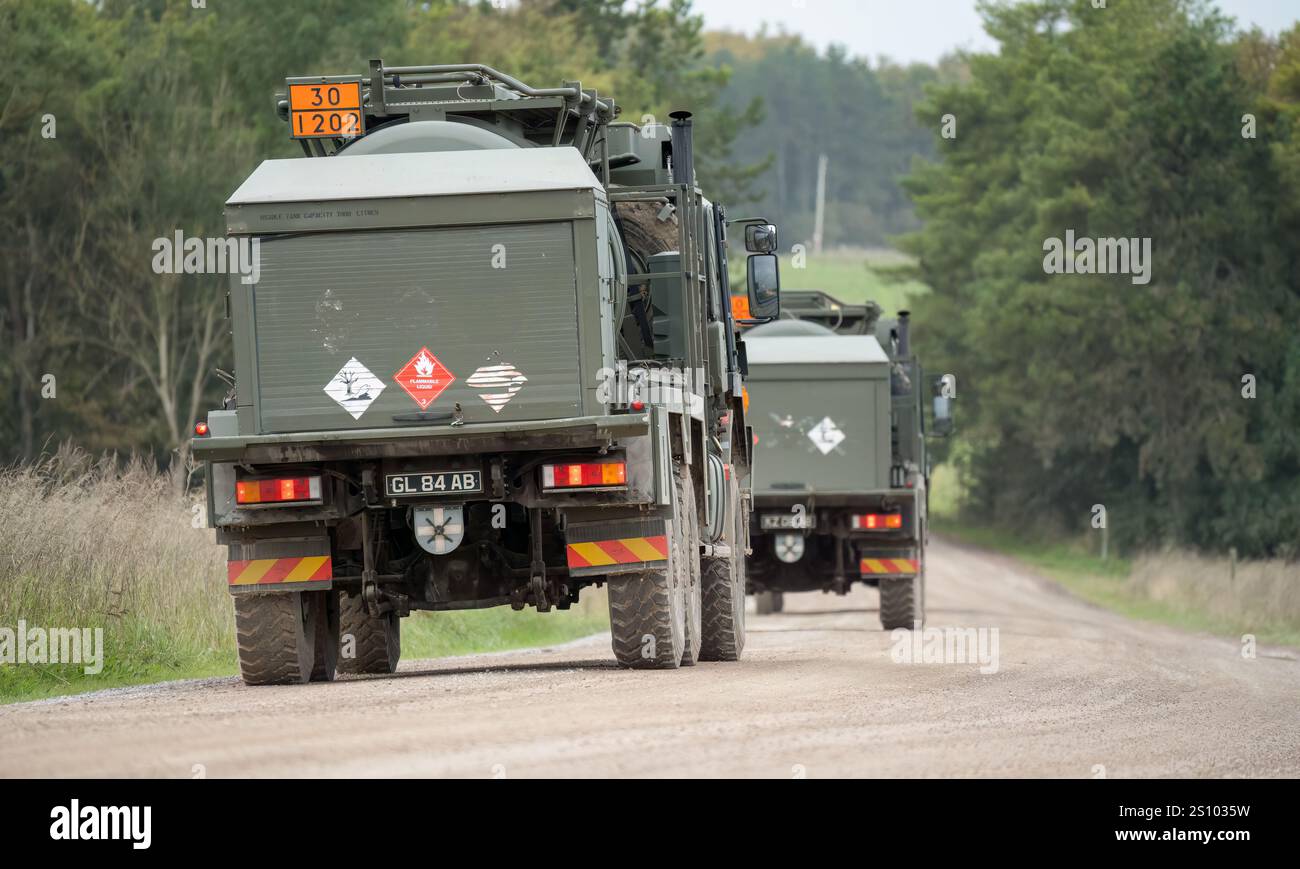 convoy of British army Heavy Utility Trucks driving along a dirt track ...