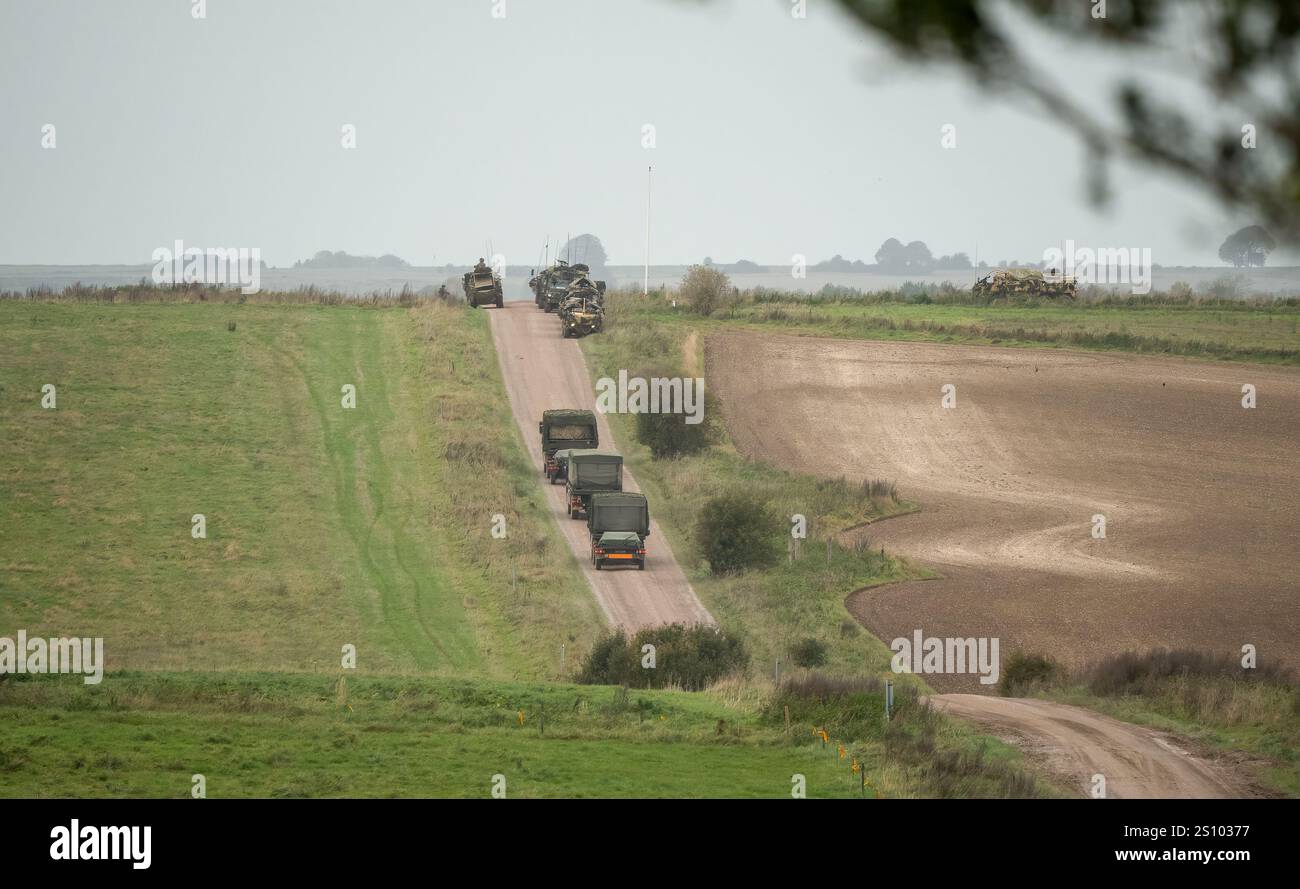 convoy of British army Heavy Utility Trucks driving along a dirt track ...