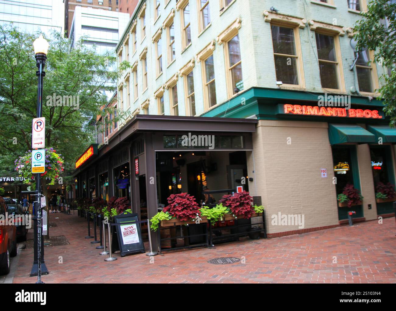 A lively restaurant with outdoor seating and colorful plants in a ...