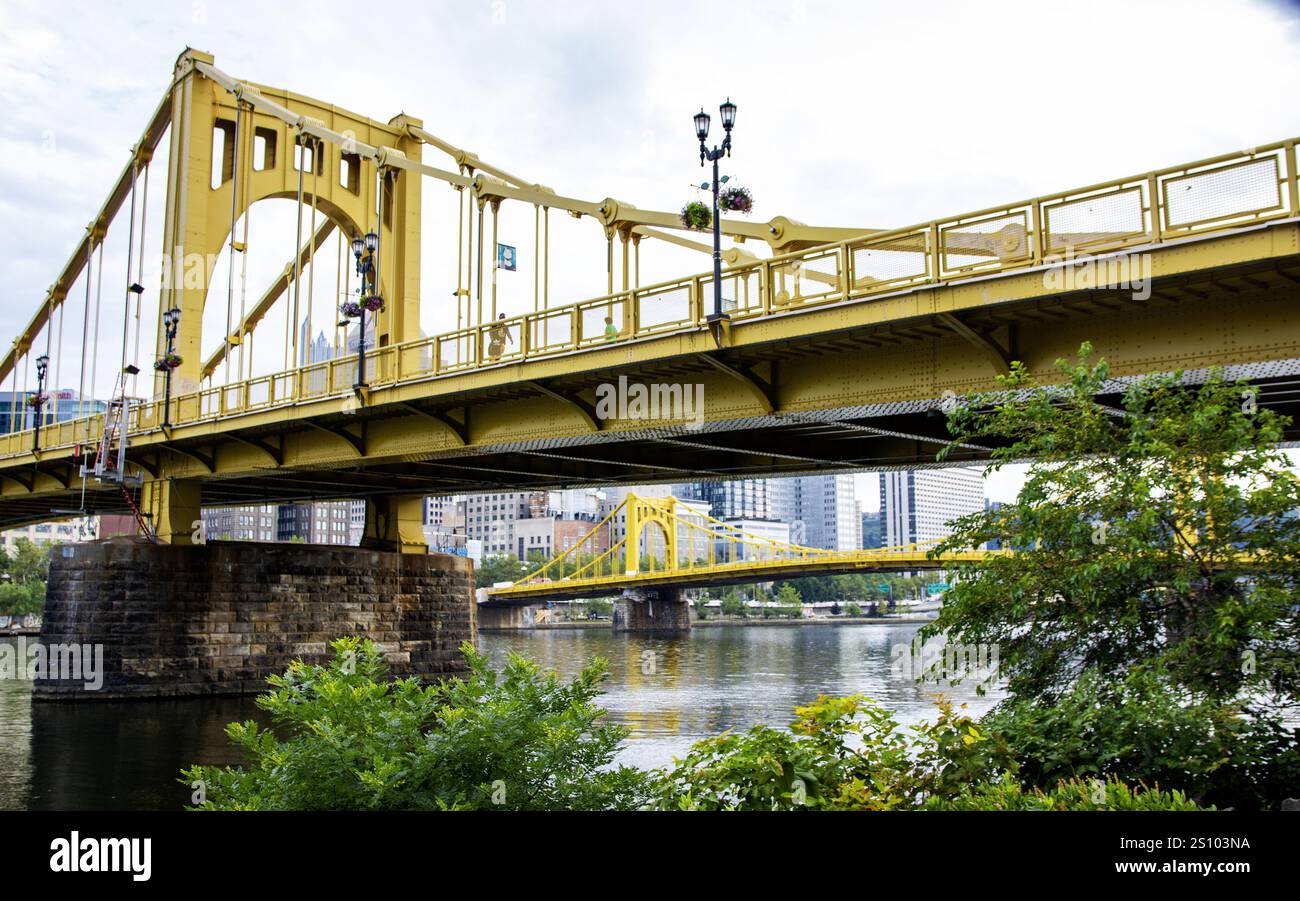 A vibrant yellow bridge spans over the river in Pittsburgh, showcasing ...