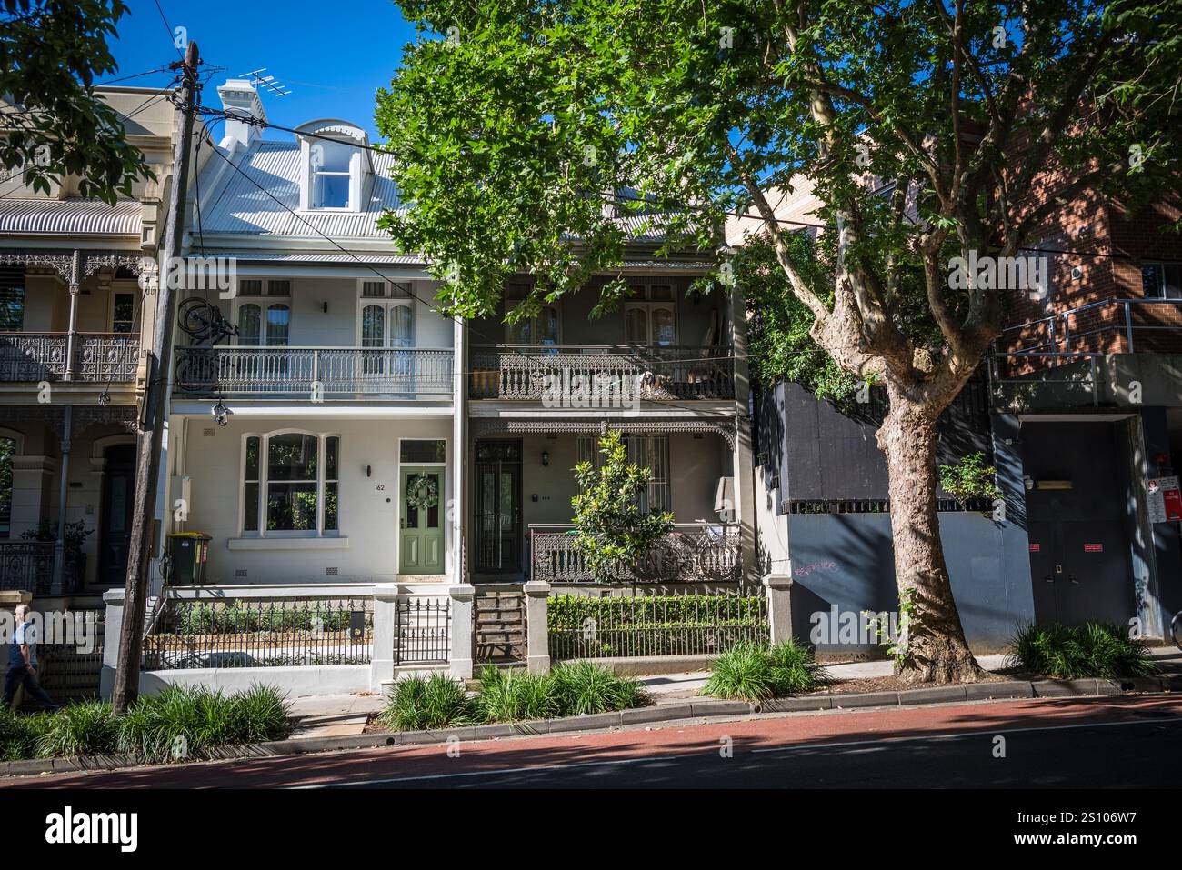 Street with Victorian-era houses adorned with ornamental iron lacework ...