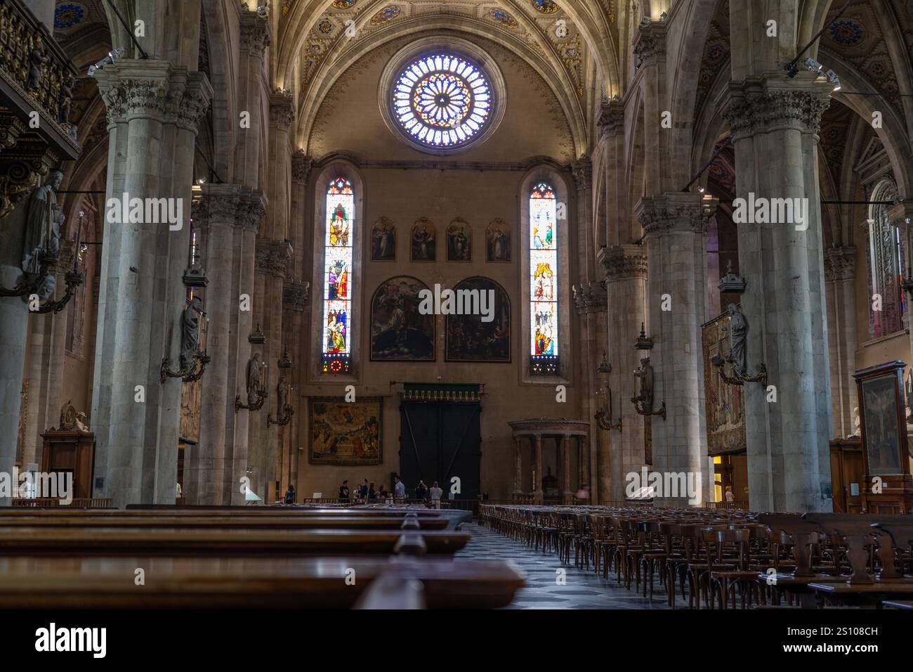 Interior of a grand cathedral with soaring stone columns, stained-glass windows, and intricate ...