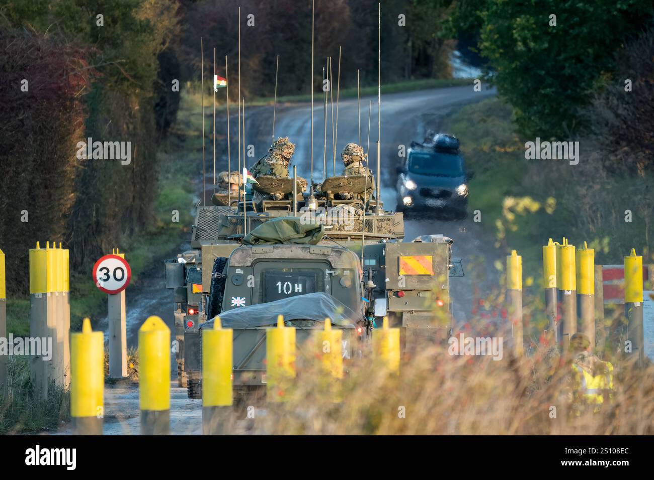 a convoy of British army tracked tansk moving along a country roadway ...