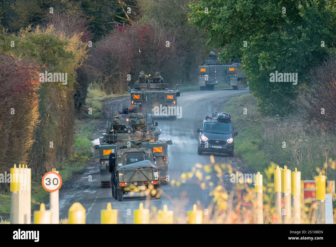 a convoy of British army tracked tansk moving along a country roadway ...