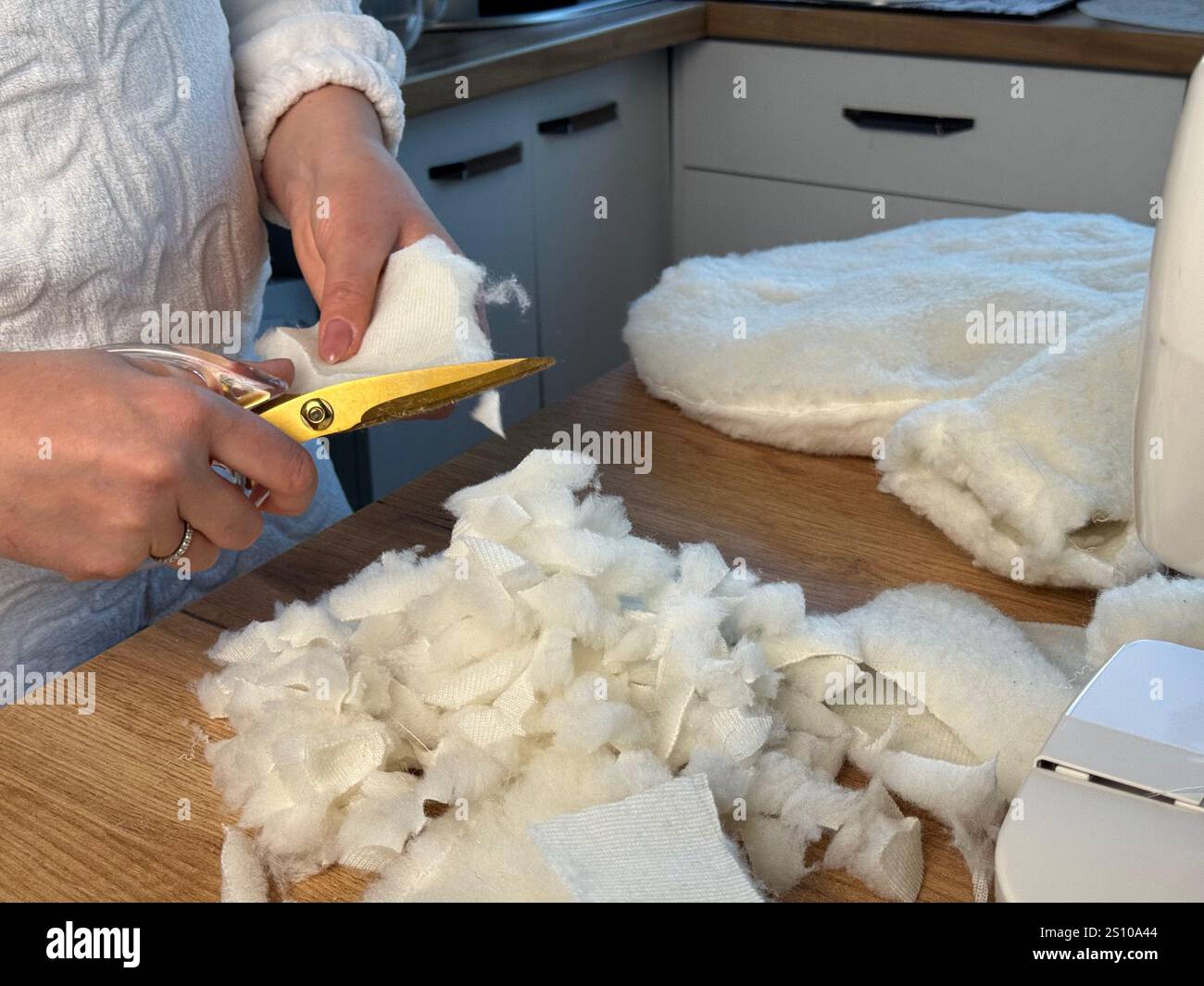A woman is making a soft filler from fabric scraps. Cutting fabric ...