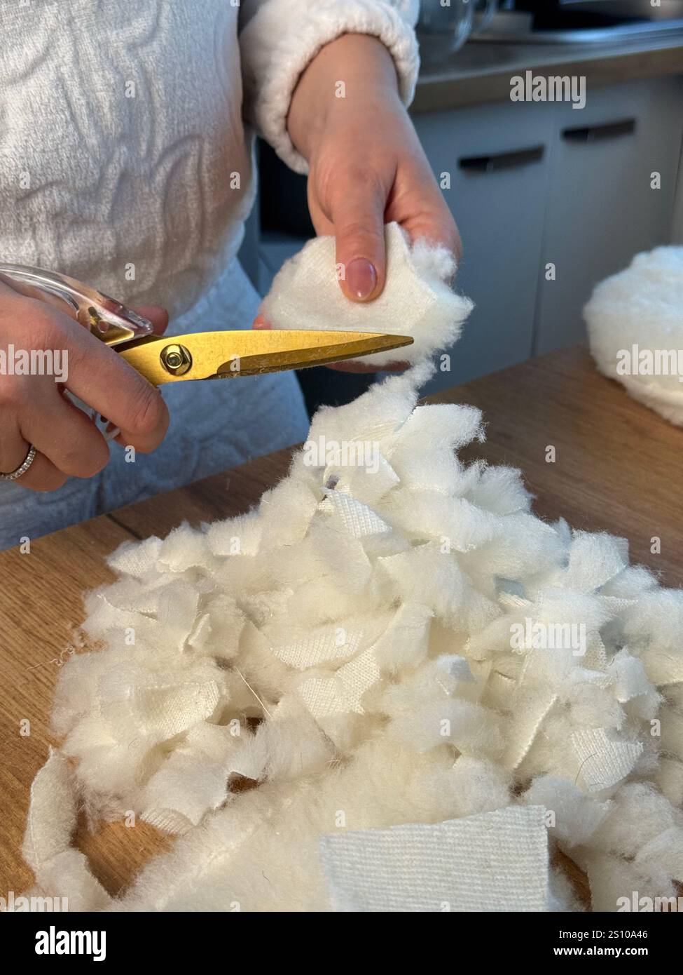 A woman is making a soft filler from fabric scraps. Cutting fabric ...