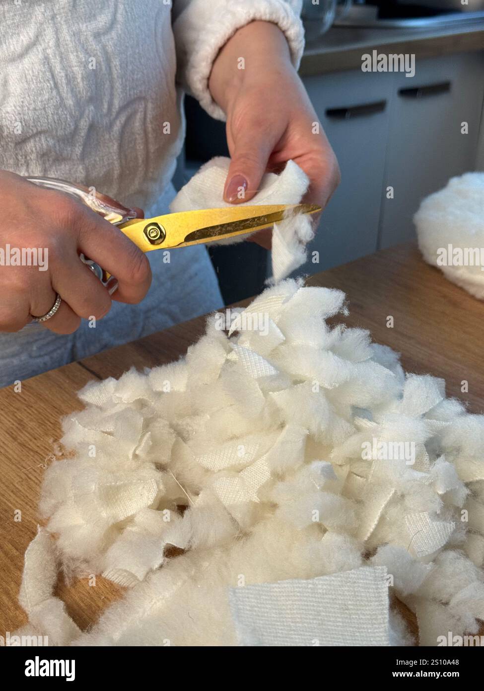 A woman is making a soft filler from fabric scraps. Cutting fabric ...