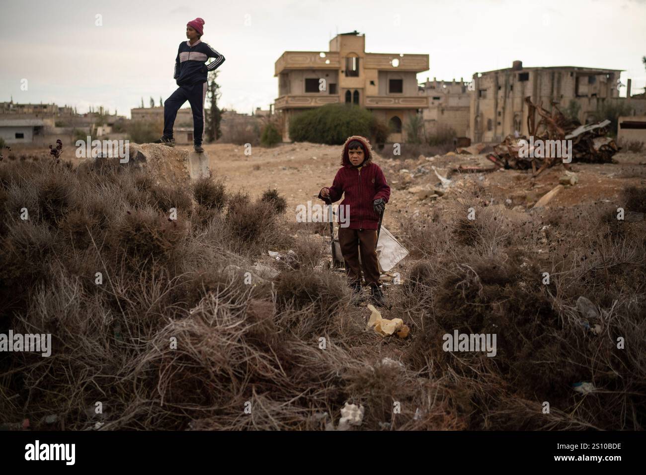 A boy looks at the photographer as members of the security forces of ...