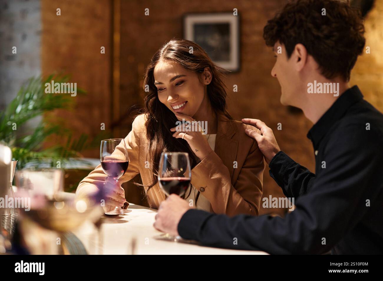 A couple shares intimate smiles and laughter while sipping wine in a ...